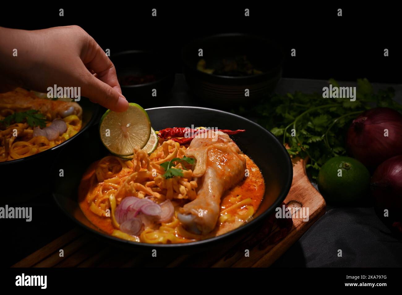 A female chef garnishing her Khao Soi Kai with a lime slide, Khao Soi ...