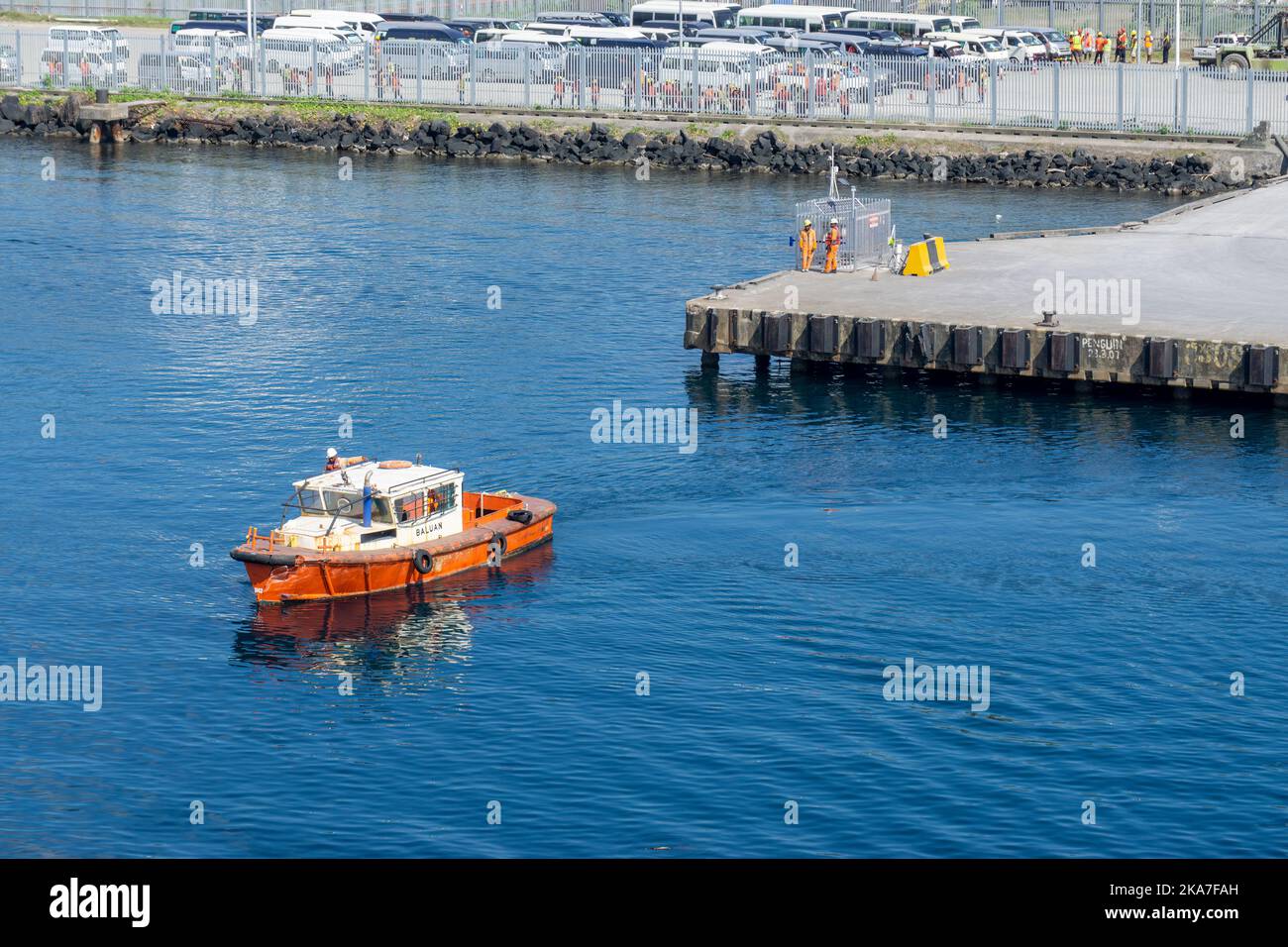 Man standing on back of orange port tender ready to receive mooring ...
