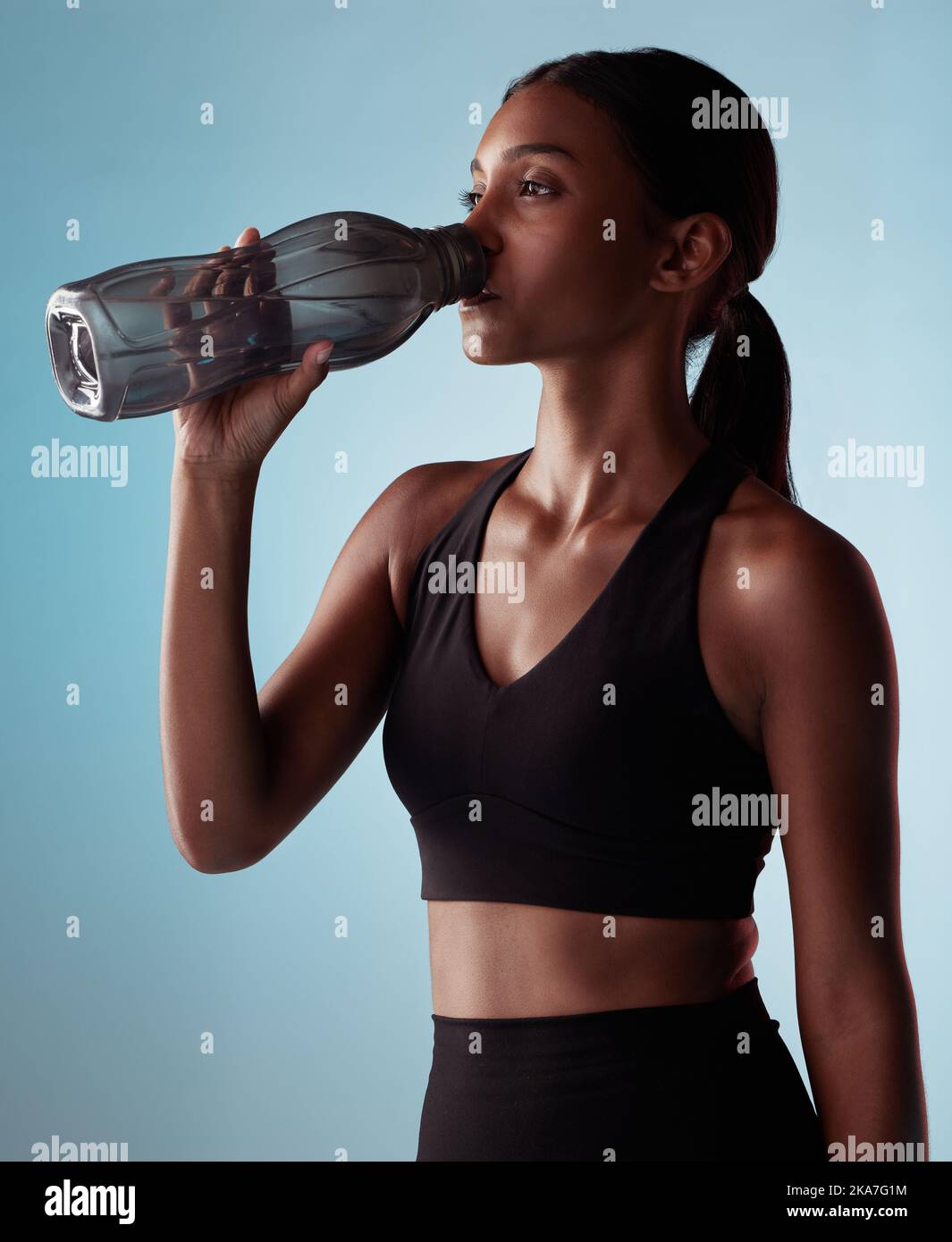 Fitness woman drinking water bottle in studio, training and workout ...