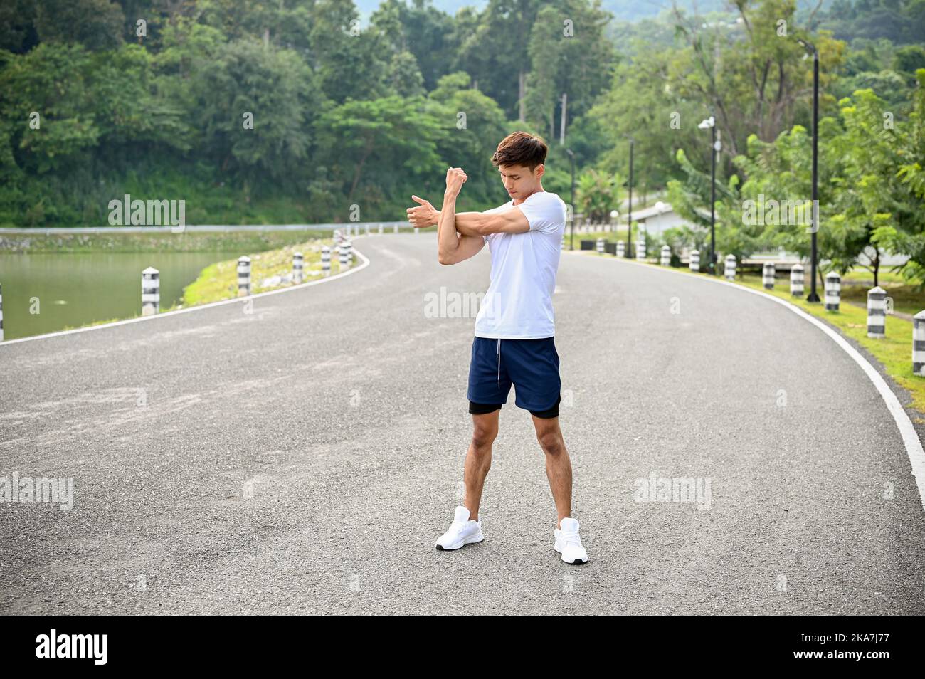 Fit and active young Asian man in sportswear starching his arms and ...