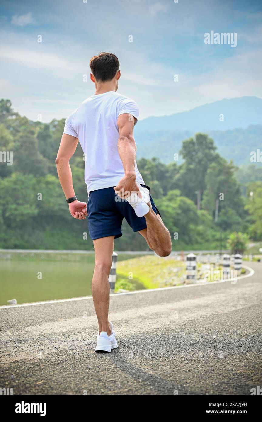 Fit and active young Asian athletic man in sportswear stretching his ...