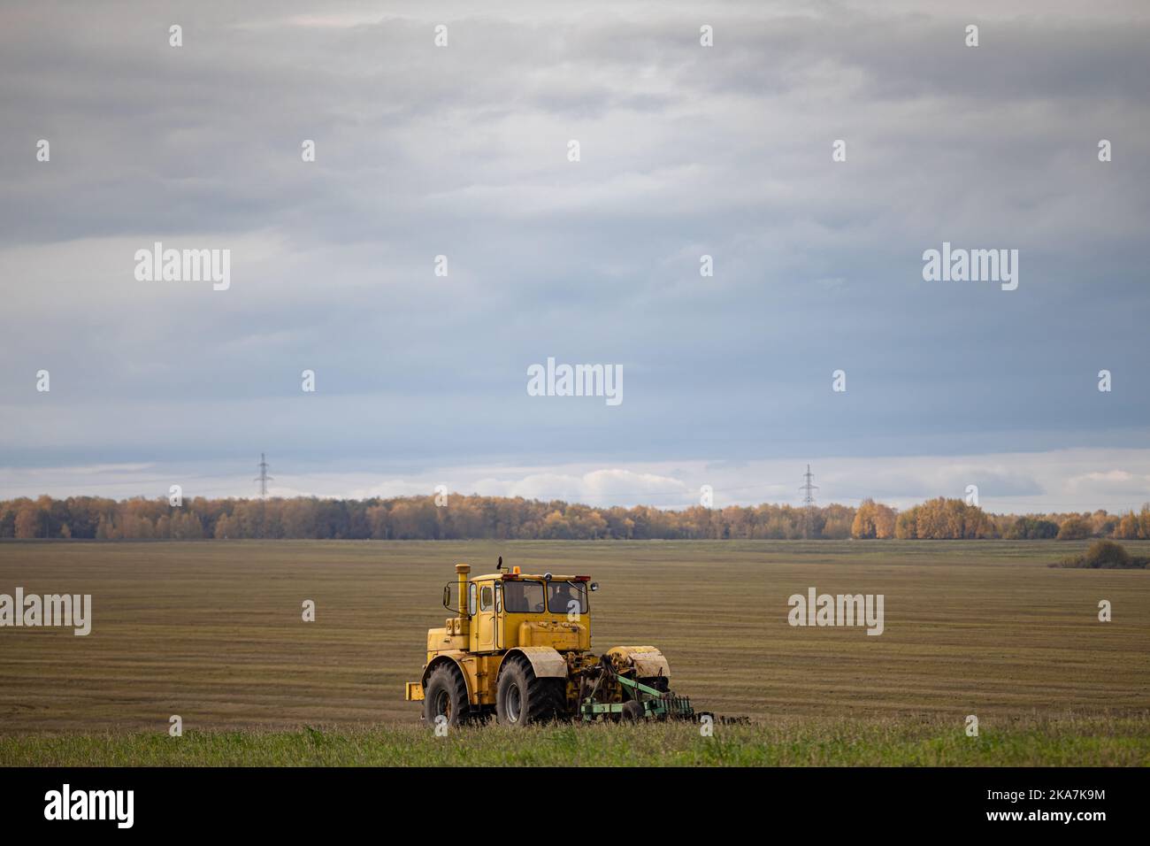 old yellow tractor running in the field. tractor plows the ground Stock ...