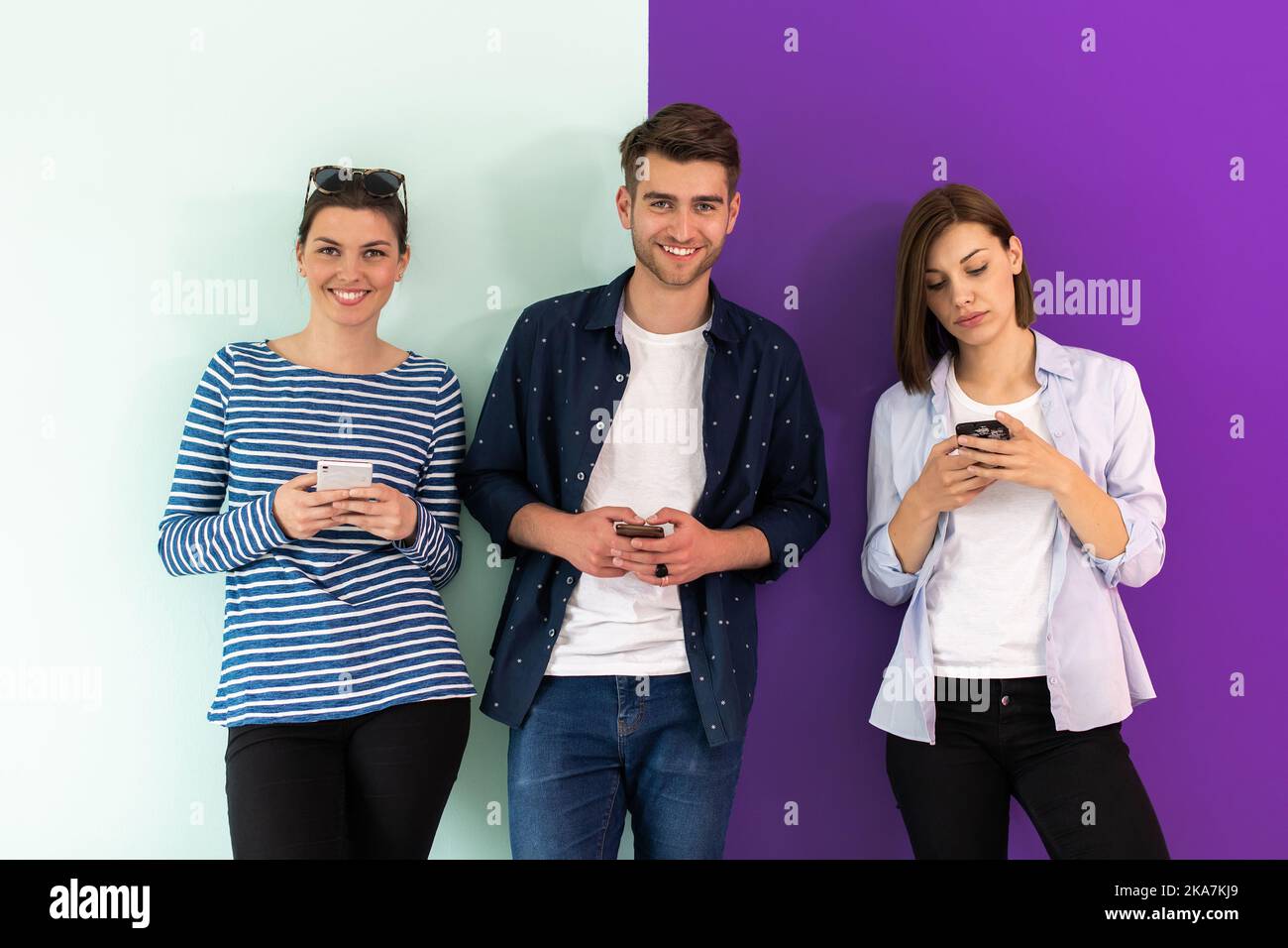 Diverse teenagers using mobile devices while posing for a studio photo ...