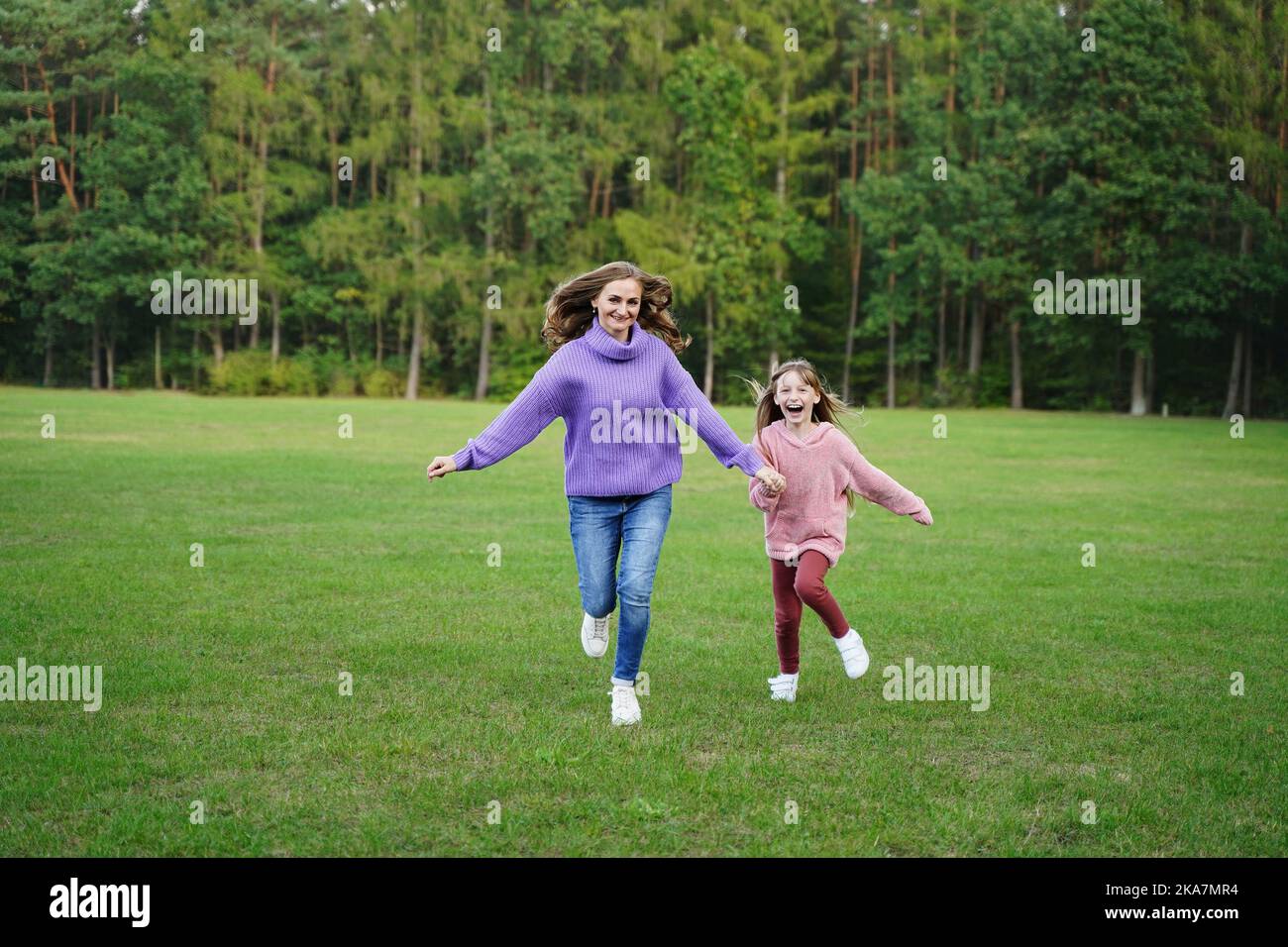 Happy mom and daughter run outdoors. Family vacation in nature. Joyful ...