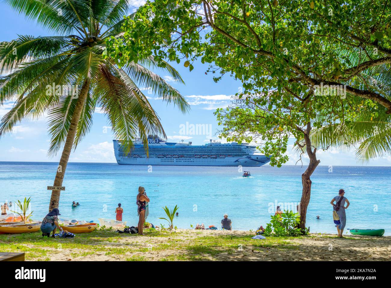 Cruise ship anchored off Conflict Islands framed by palm trees, Papua ...