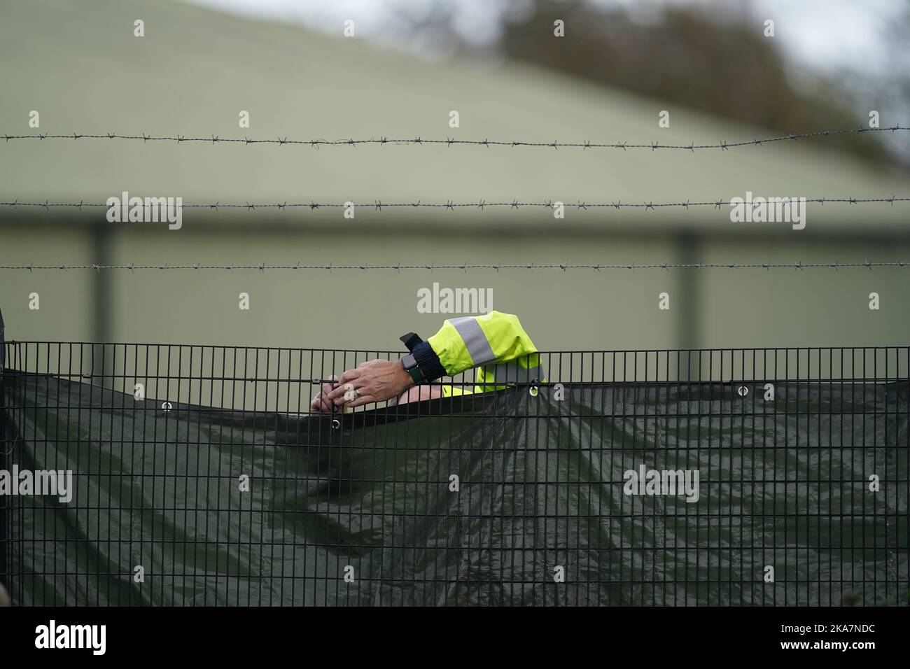 A member of security staff secures screens around the Manston ...