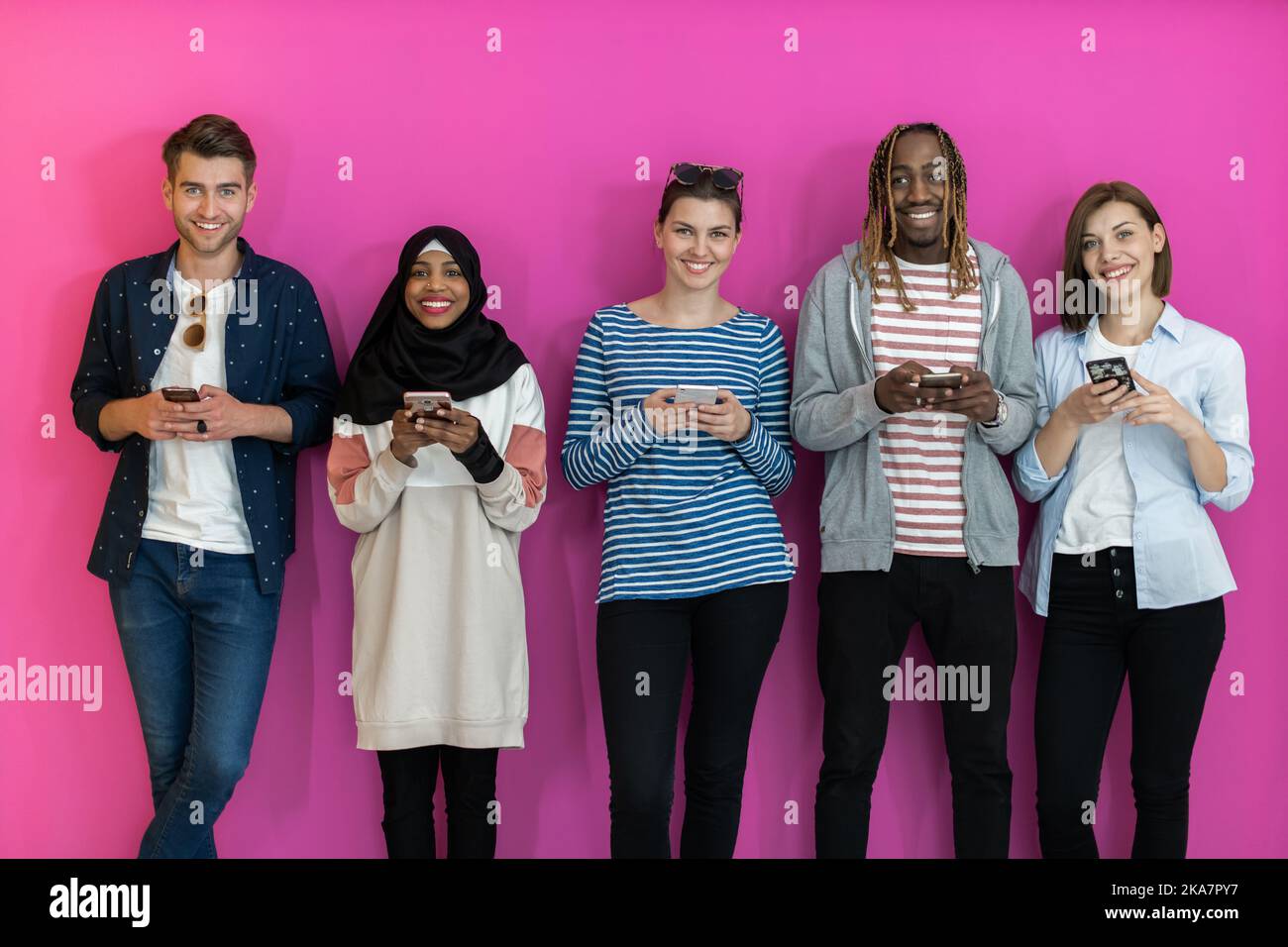 Diverse teenagers using mobile devices while posing for a studio photo ...
