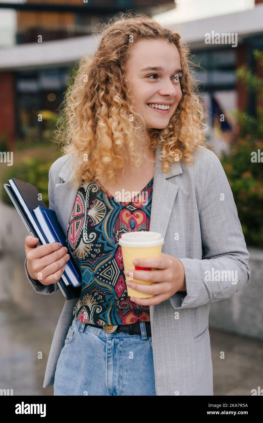 Portrait of girl student standing at university campus smiling, looking ...