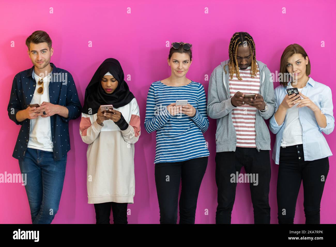 Diverse teenagers using mobile devices while posing for a studio photo ...