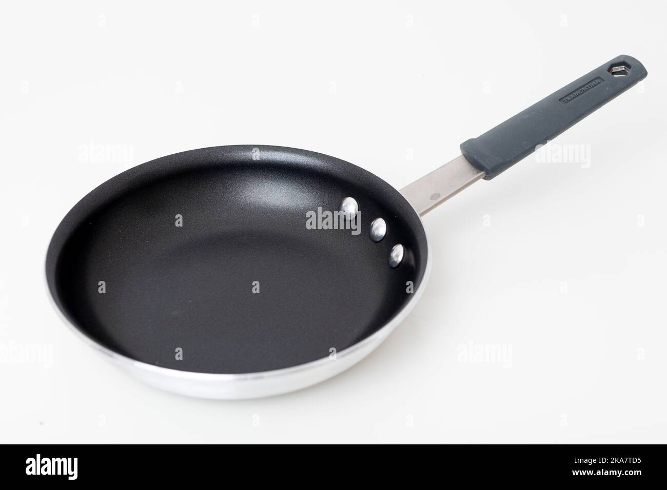 A stainless steel non-stick frying pan shot against a plain white ...