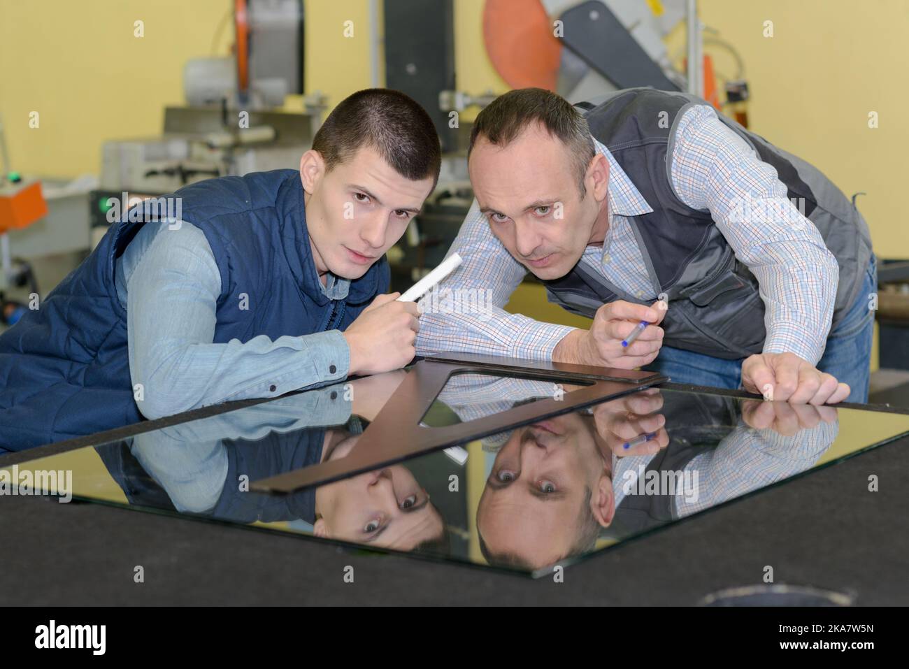 professional debonair worker and apprentice toiling on a machine Stock ...