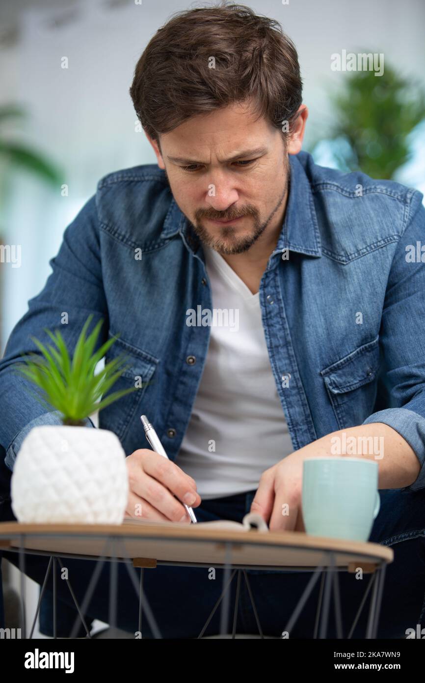 young man writing down note on the sofa Stock Photo - Alamy