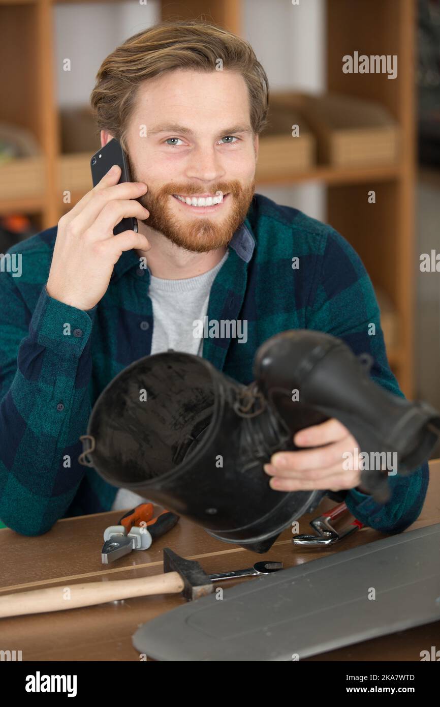 mechanic holding a car part and using a smartphone Stock Photo - Alamy