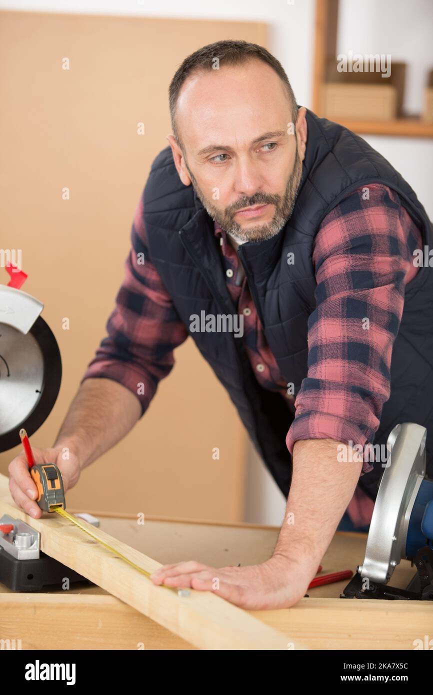 male master measuring a wood piece in factory Stock Photo - Alamy