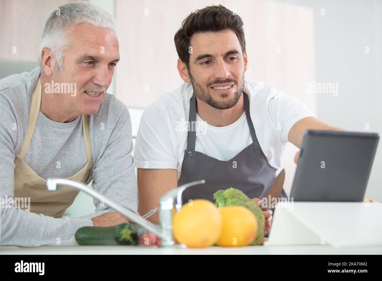 young son and senior father cooking with tutorial Stock Photo - Alamy