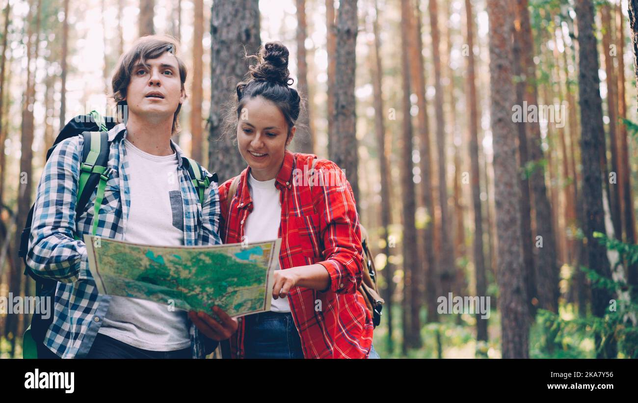 Lost tourists are standing in forest looking at map, talking and ...