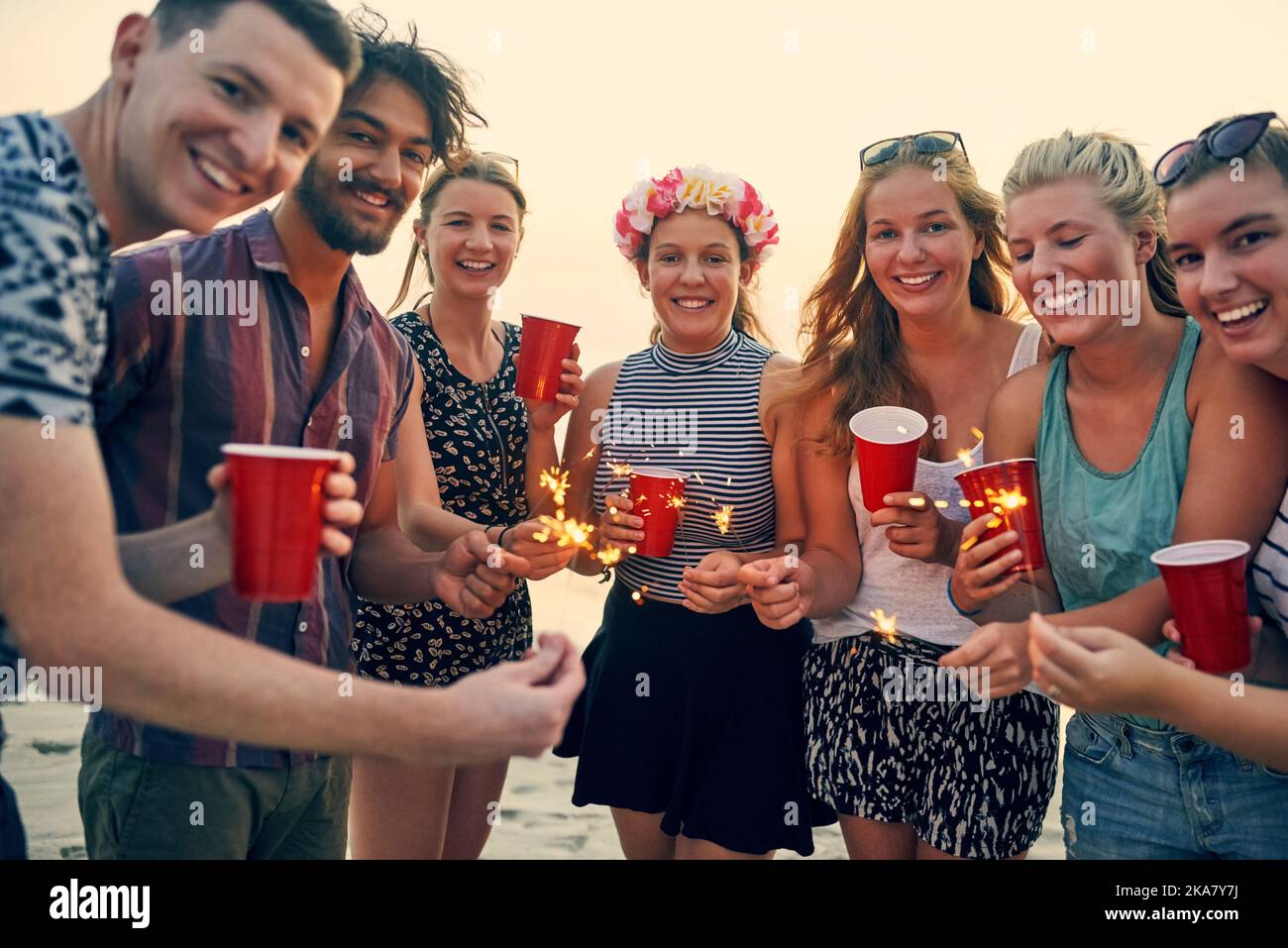 Ending the day with some sparkle. young people hanging out at the beach ...