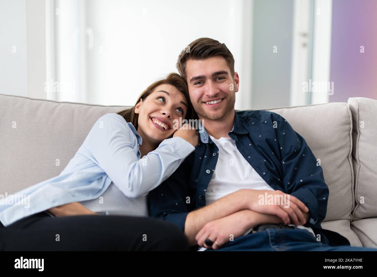 Couple Watches TV together while Sitting on a Couch in the Living Room ...