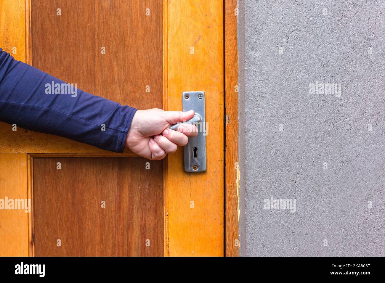 Wood door with human hand holding gripping the handle to open and enter ...