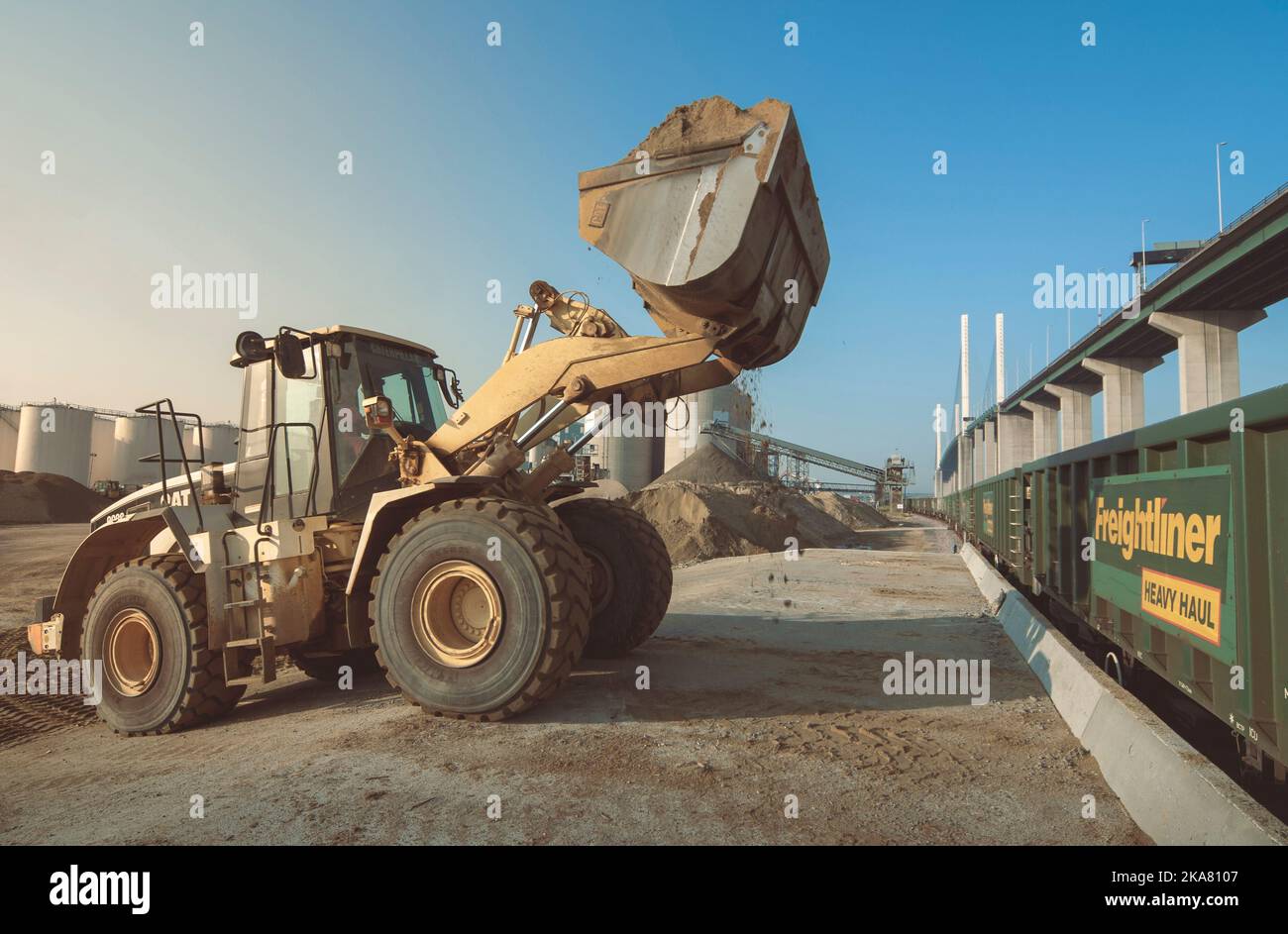 Caterplillar wheel loader loading aggregate wagons on a Freightliner ...