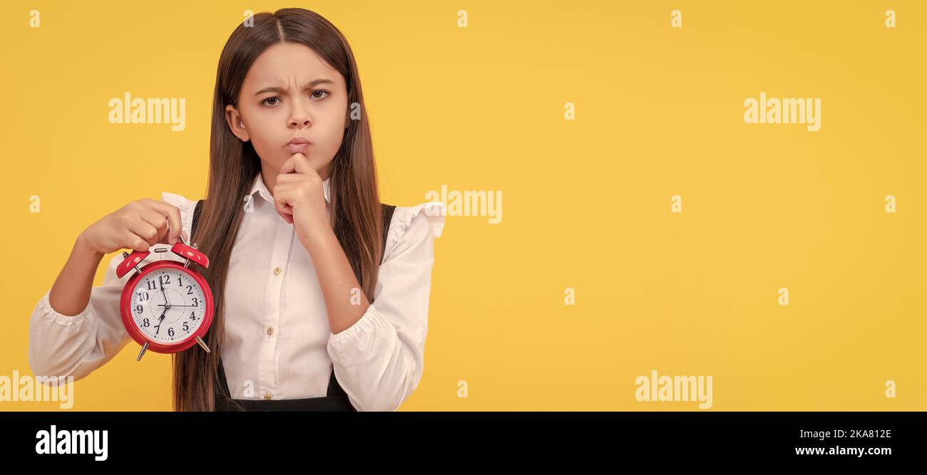pondering child with alarm clock. school kid in uniform showing time ...