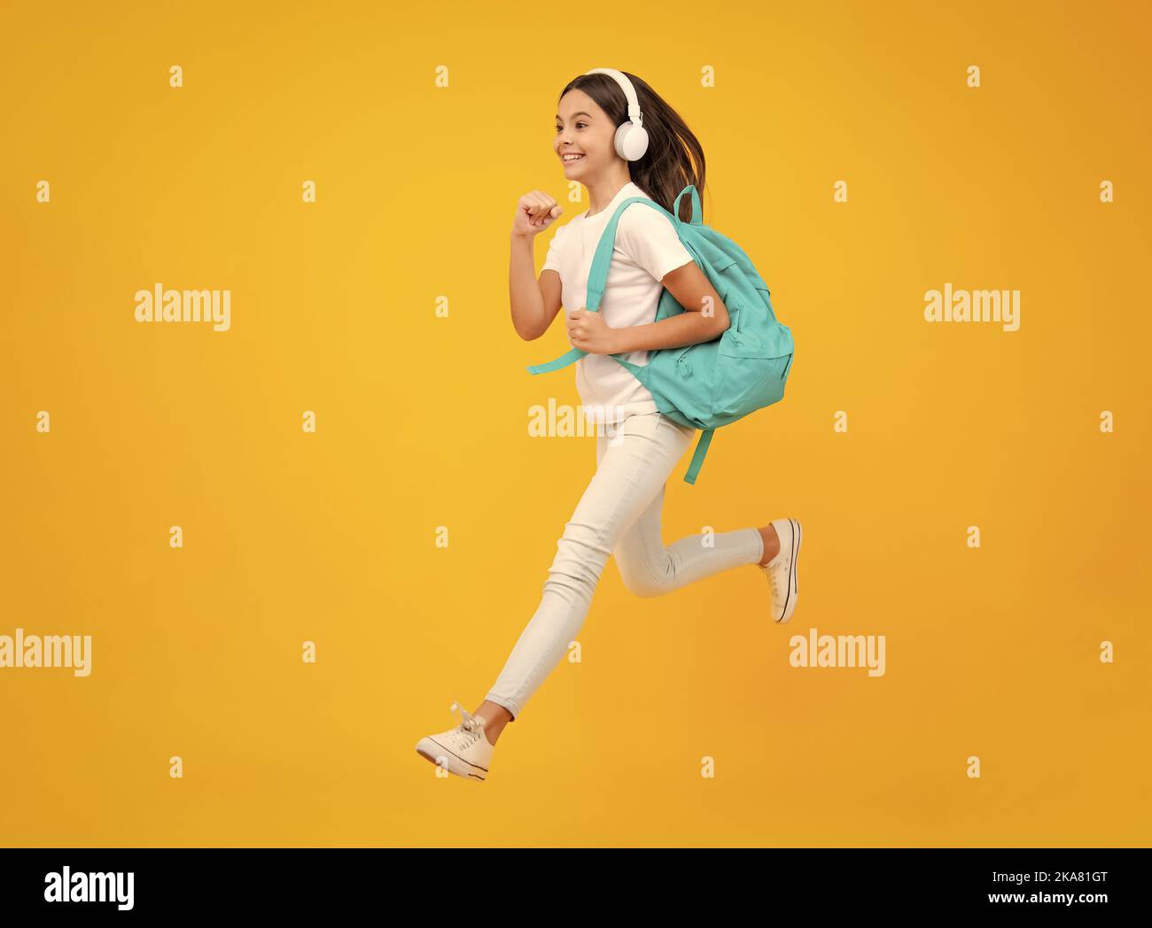 Happy teenager portrait. School girl in headphones on isolated studio ...