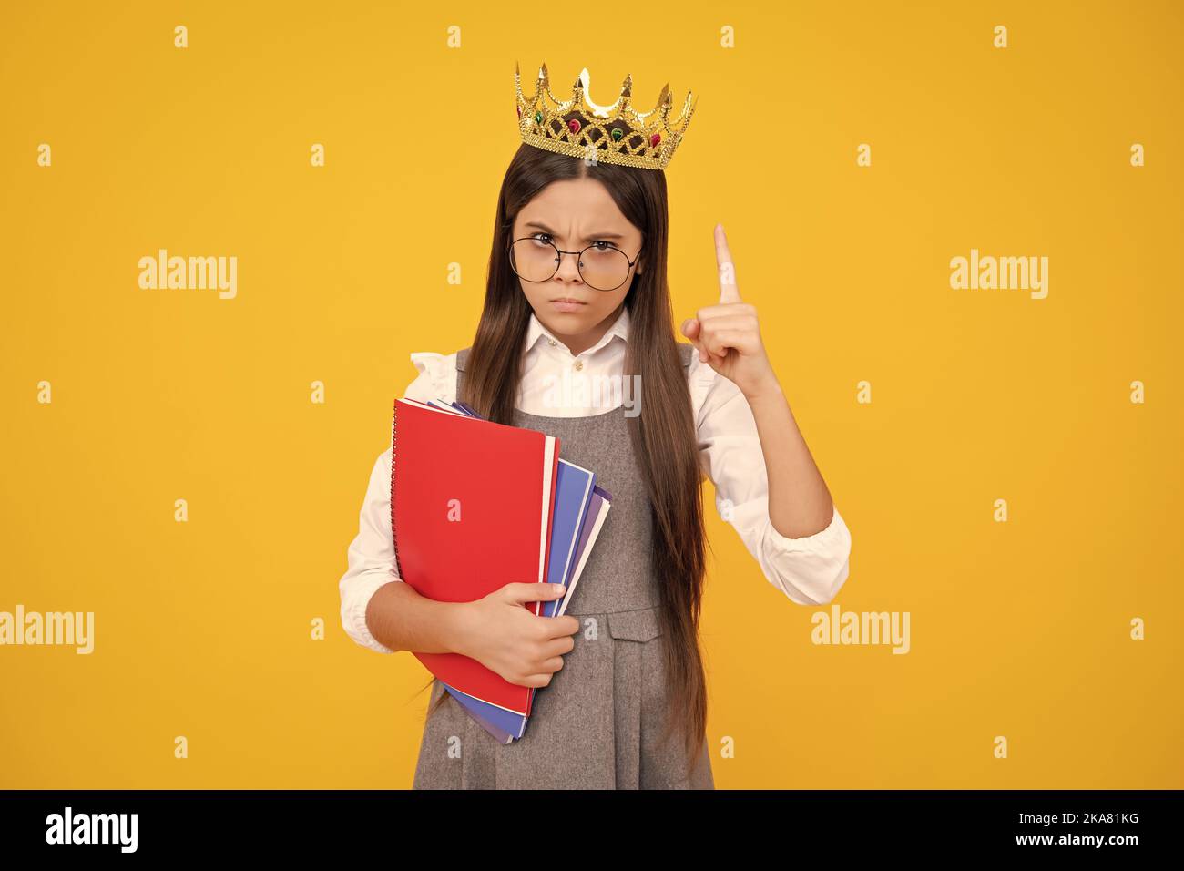 Schoolgirl in school uniform and crown celebrating victory on yellow ...