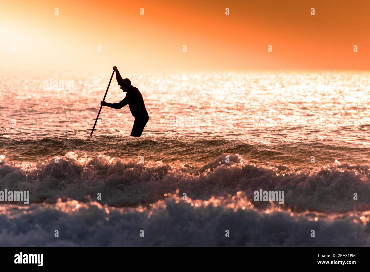 A paddle boarder silhouetted by a spectacular sunset at Fistral Beach ...