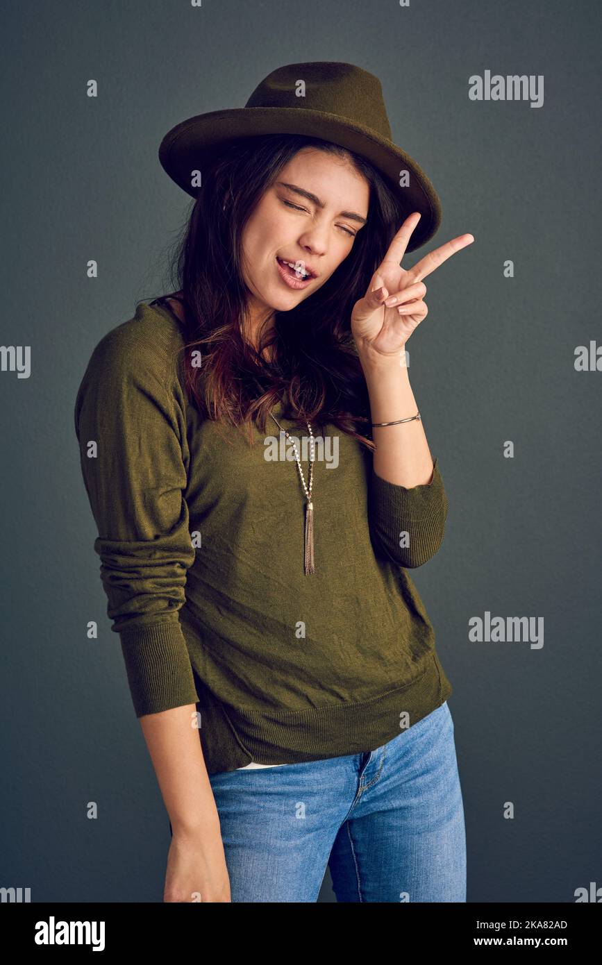Peace out everyone. Studio shot of a carefree young woman posing with a ...