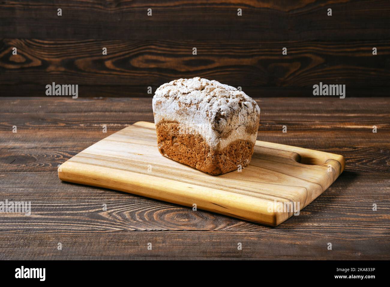 Loaf of artisan rye bread with flour topping on wooden cutting board ...