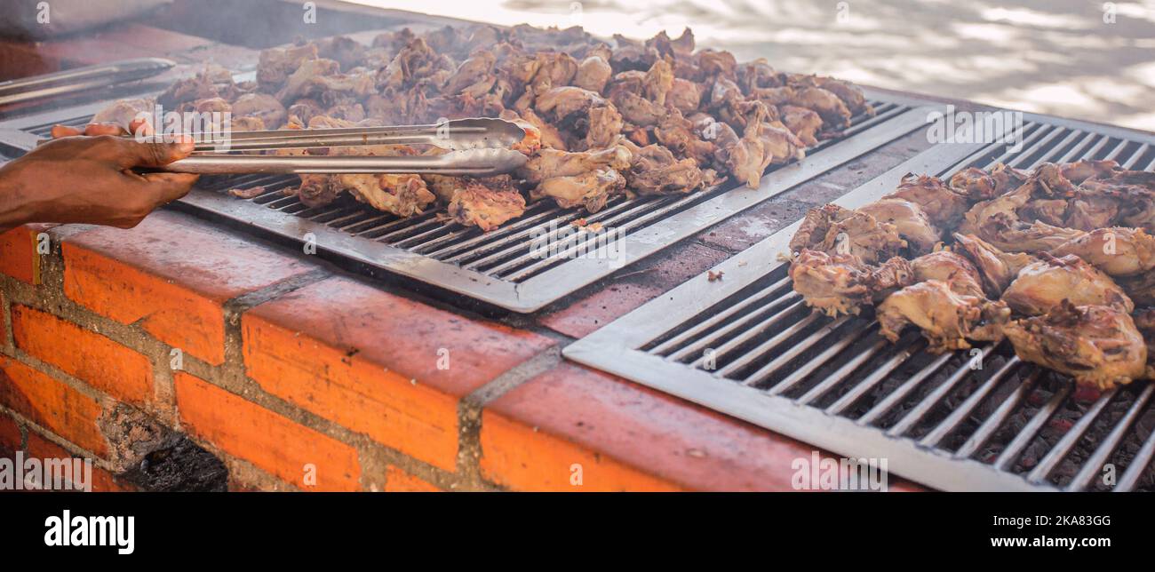 Anonymous African American male using tongs to turn chicken wings on ...