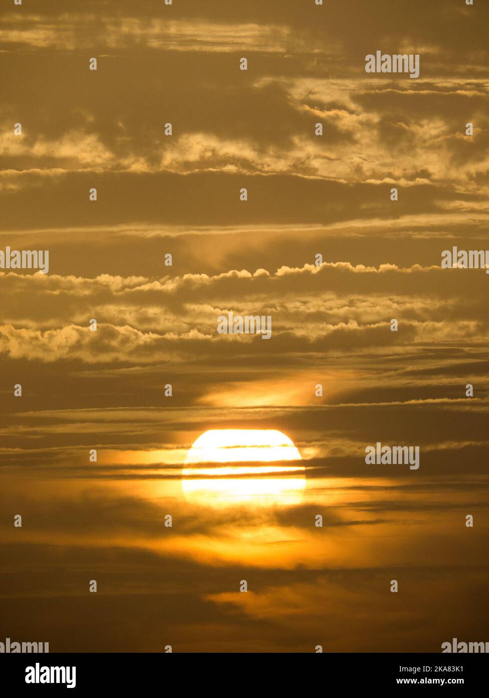 A vertical shot of yellow sunset sky with clouds and sun Stock Photo ...