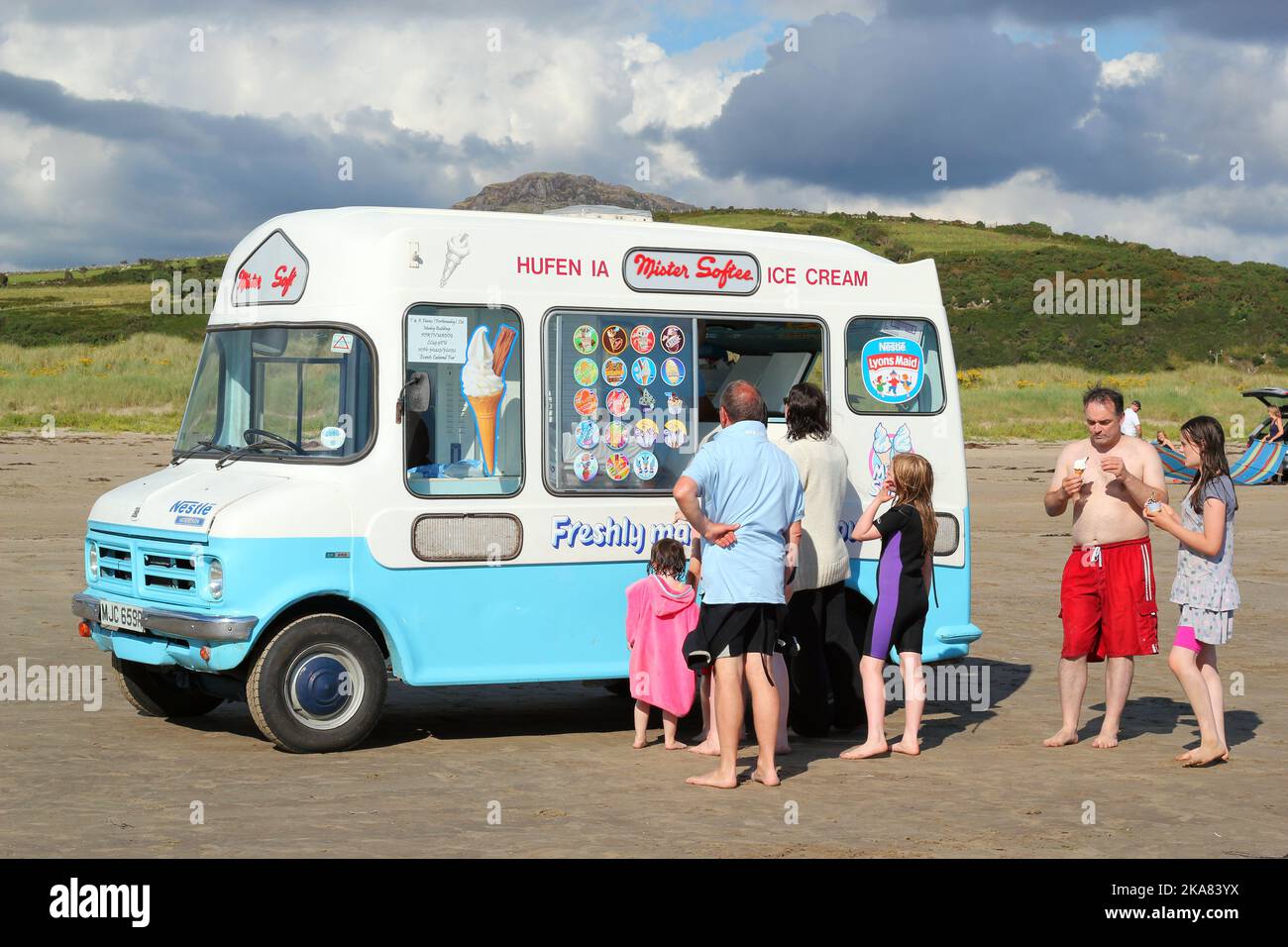 Ice cream van on a beach in Wales. People queueing for ice creams on a ...