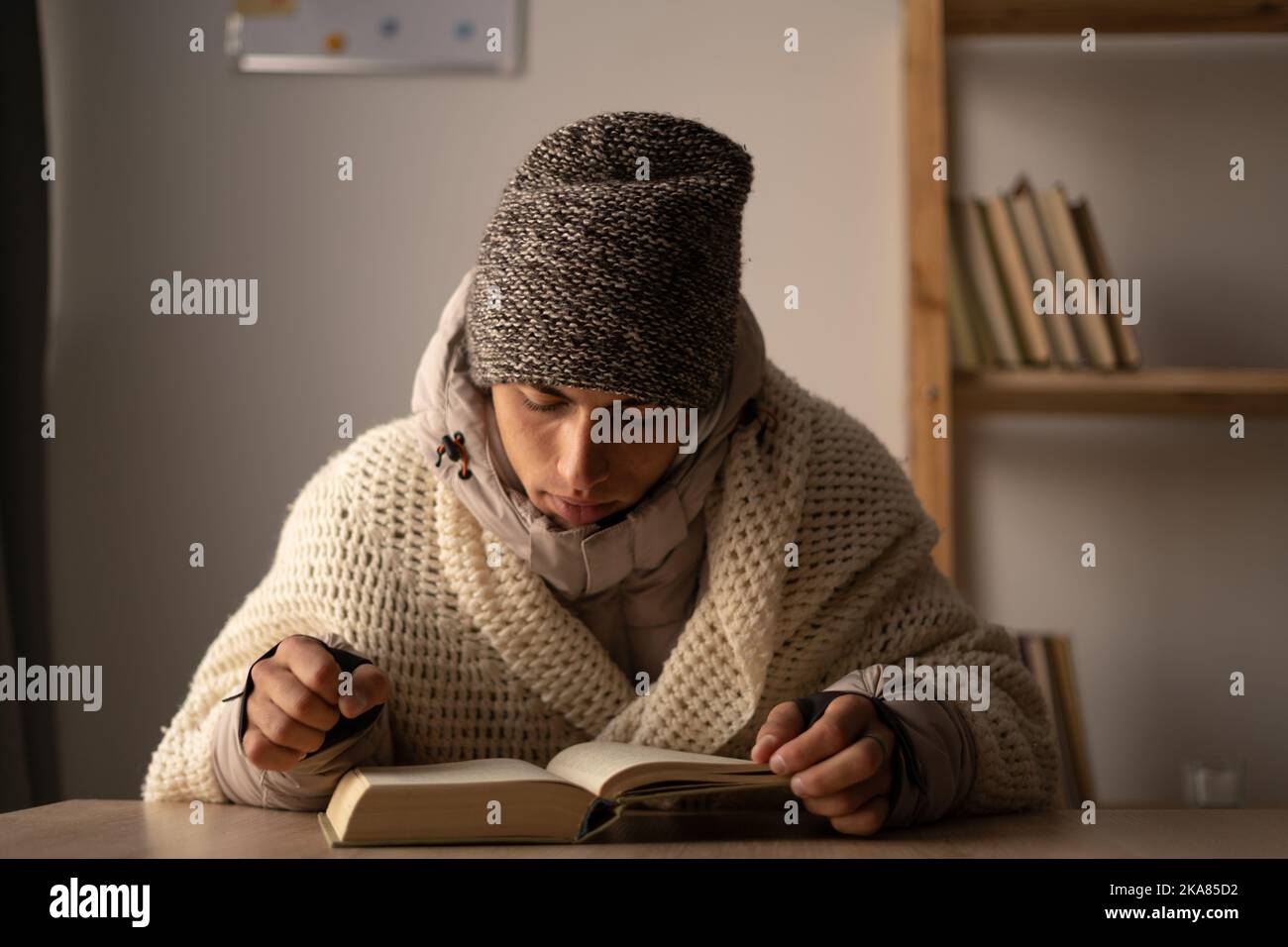 Man student dressed in winter clothes feeling cold reading book sitting ...