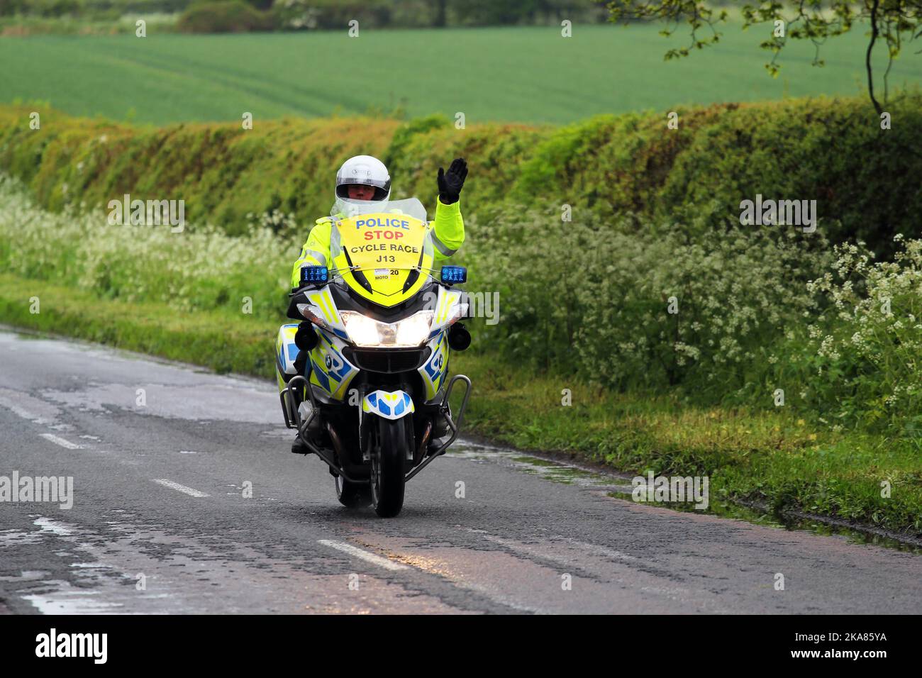 Motorcycle Policeman riding his motorbike and waving as he passes by ...