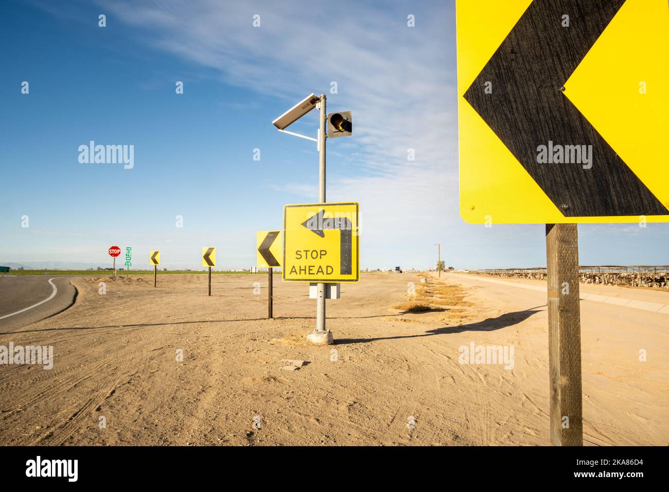 A yellow Stop Ahead sign on the side of a road in the desert area in ...