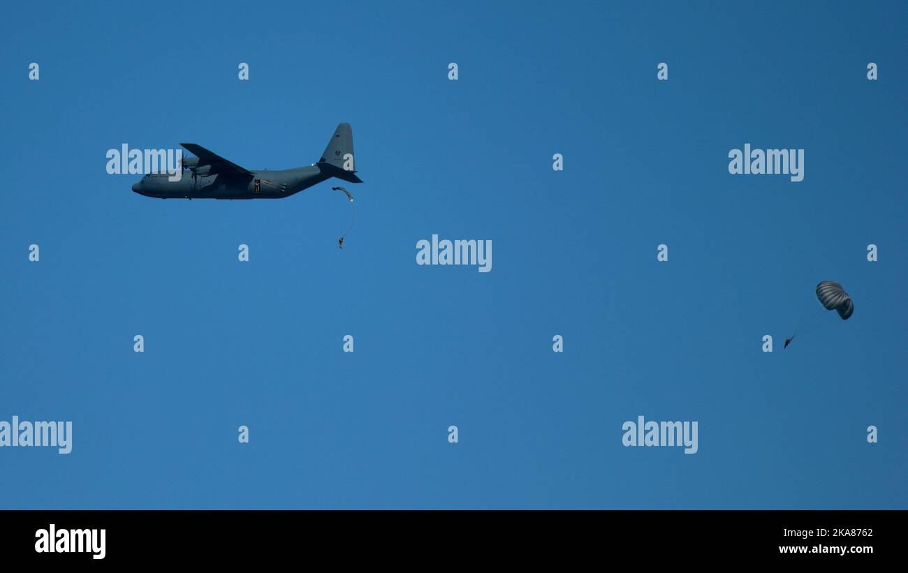 A military personnel parachuting from a RAAF aircraft in blue sky ...