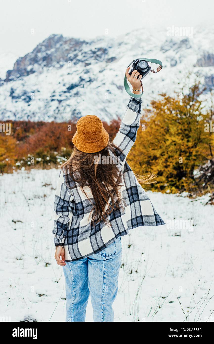 A vertical back view of a young female photographer holding her camera ...