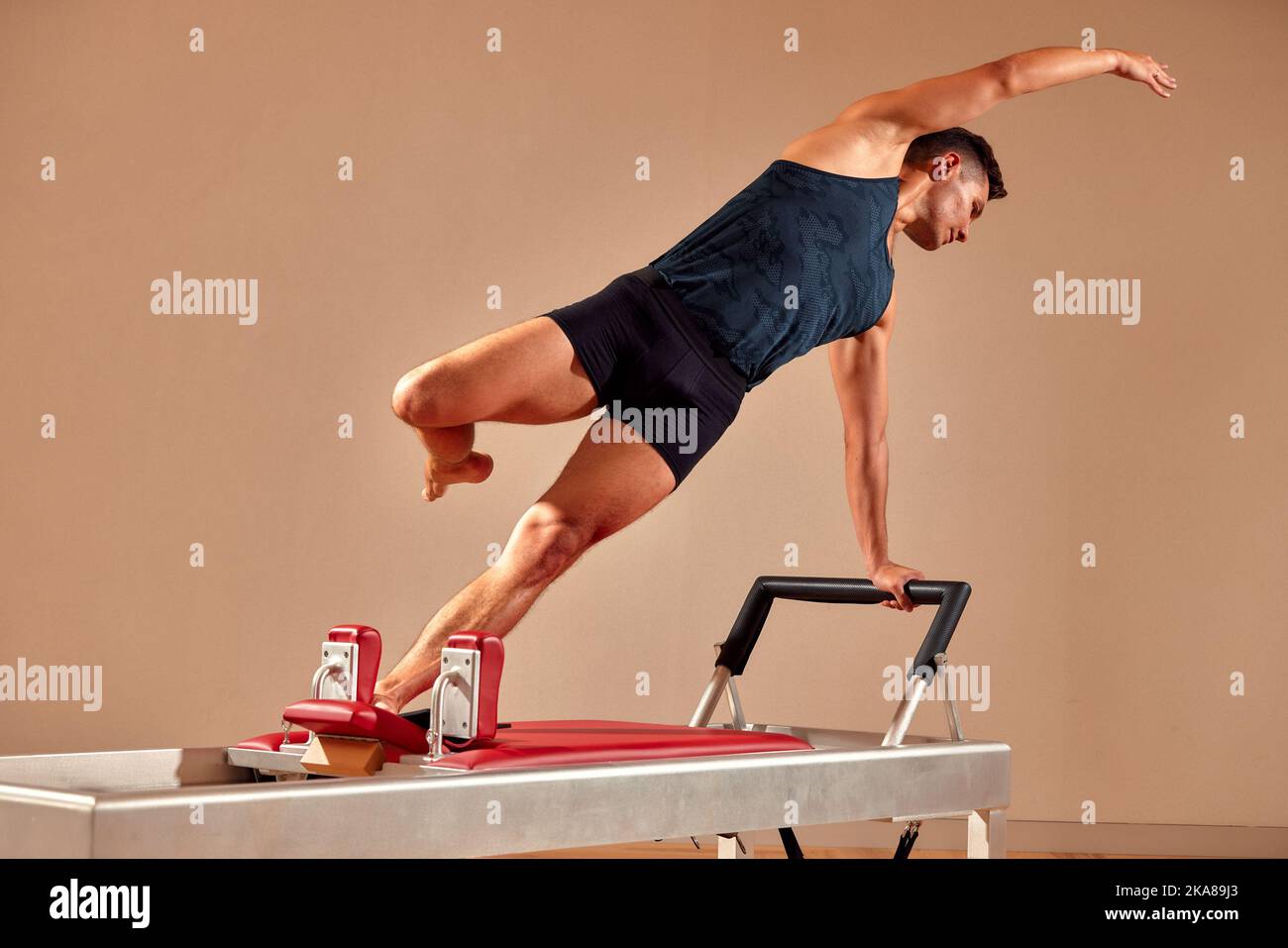 Handsome pilates male instructor performing stretching balance fitness ...