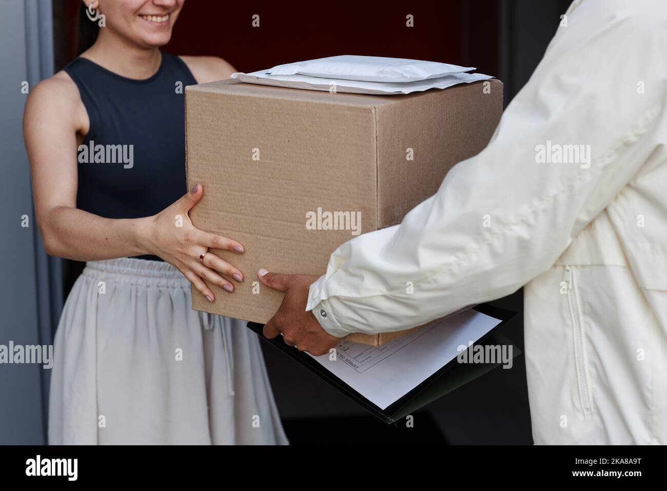Close up of delivery man handing box to smiling woman in house Stock ...
