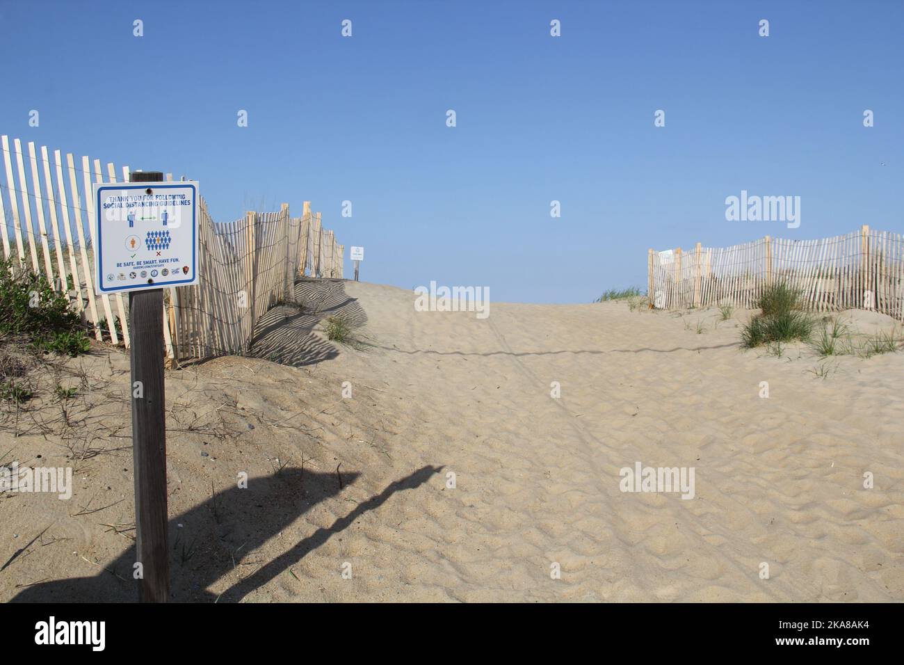 A sandy path with signs surrounded by fence on a sunny day Stock Photo ...