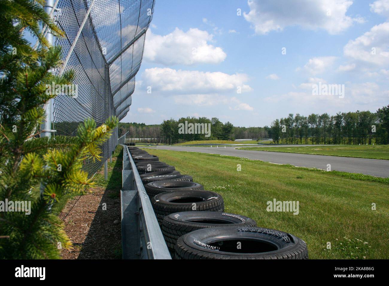 A car race track lined with tire barrier on a bright sunny day next ...