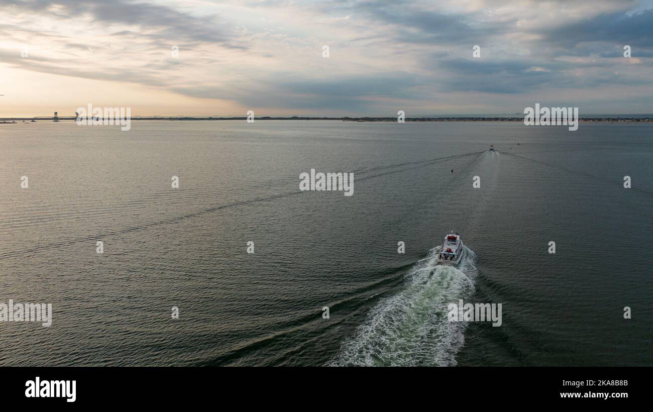 An aerial view of a fishing boat heading out to sea at sunrise on a ...