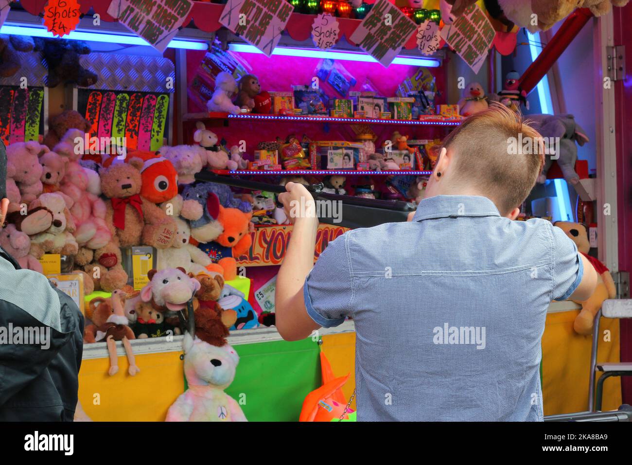 Boy shooting a gun on a rifle range trying to win prizes at a fair ...