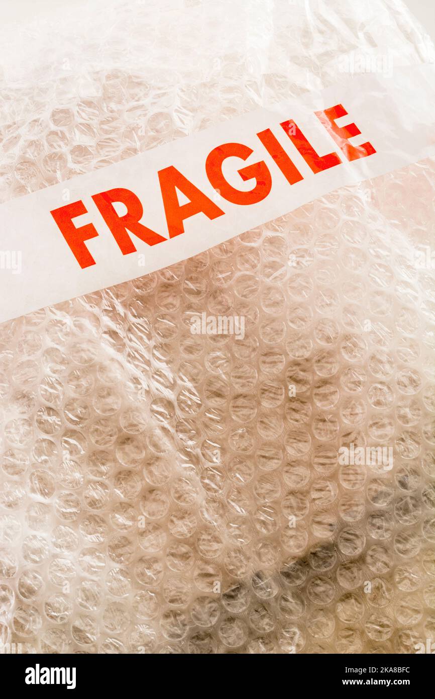 'Fragile' sticky tape labelling on plastic padded packing material or ...