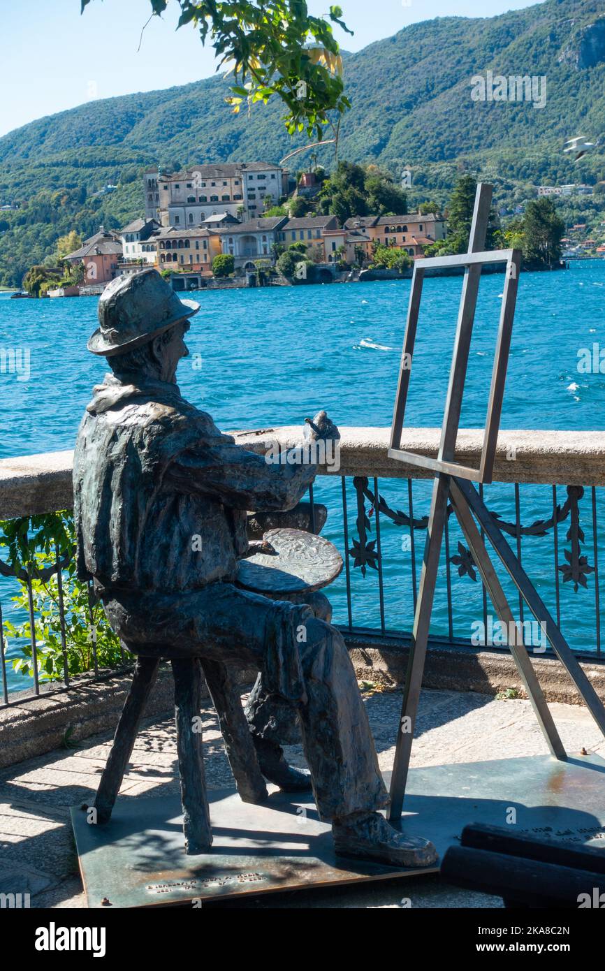 Sculpture of an artist looking across Lake Orta, in Italy, to the Isola ...
