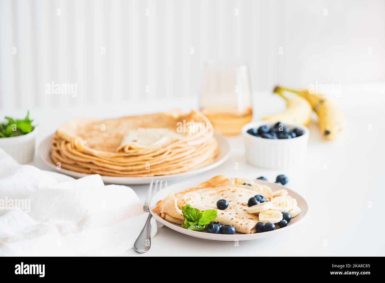 French crepes with banana and blueberries on white table. Copy space ...
