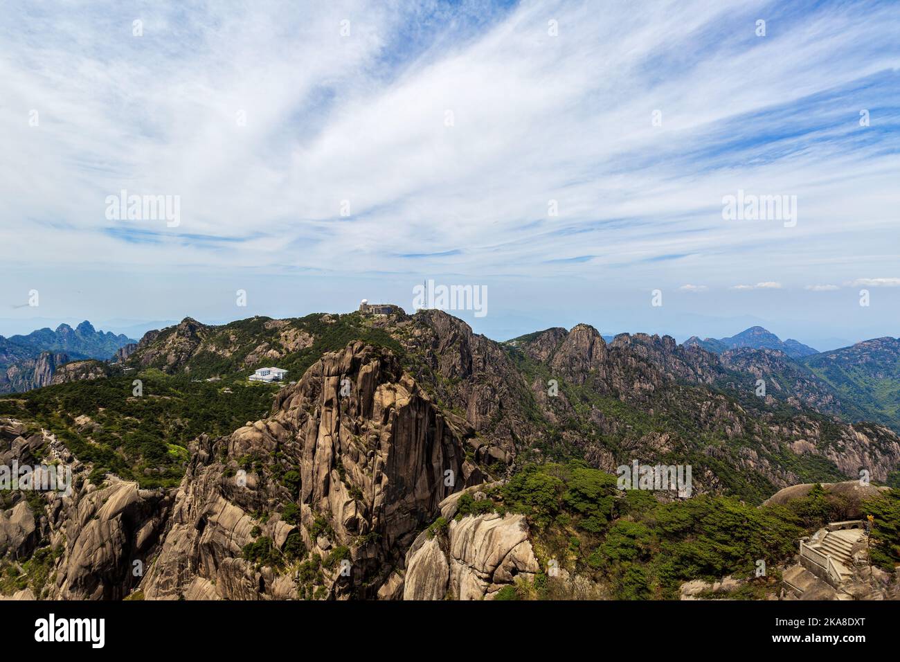 A scenic view of Huangshan mountain covered with trees against blue sky ...