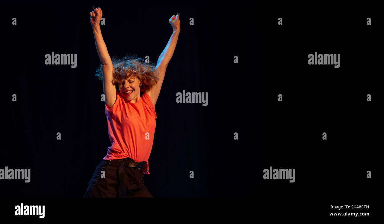 Young expressive emotional girl with short curly red hair dancing ...