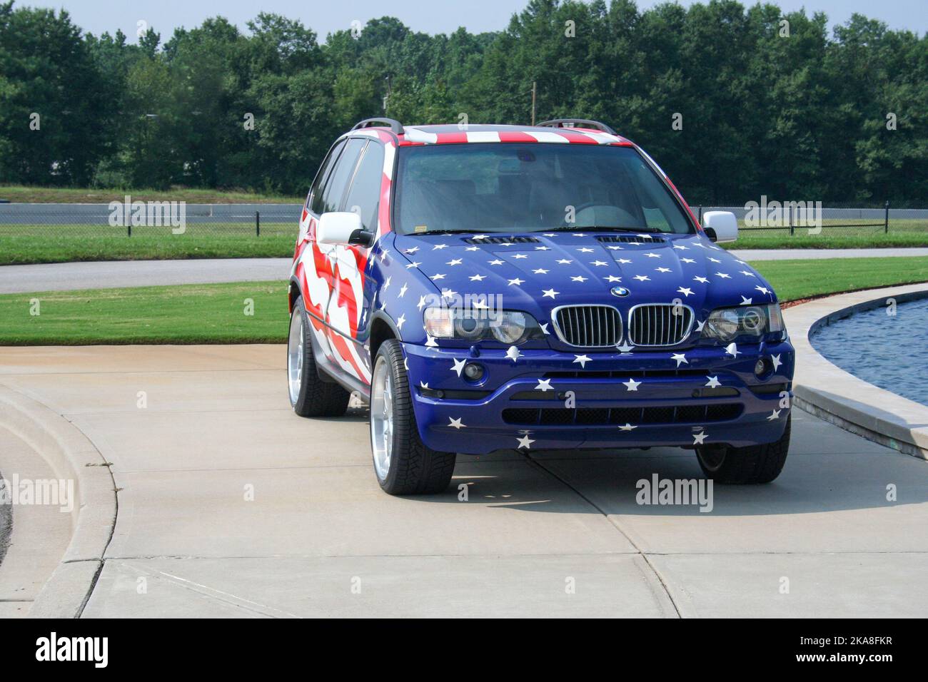 A 2006 BMW X5 car painted in the American Flag parked on a curb outside ...